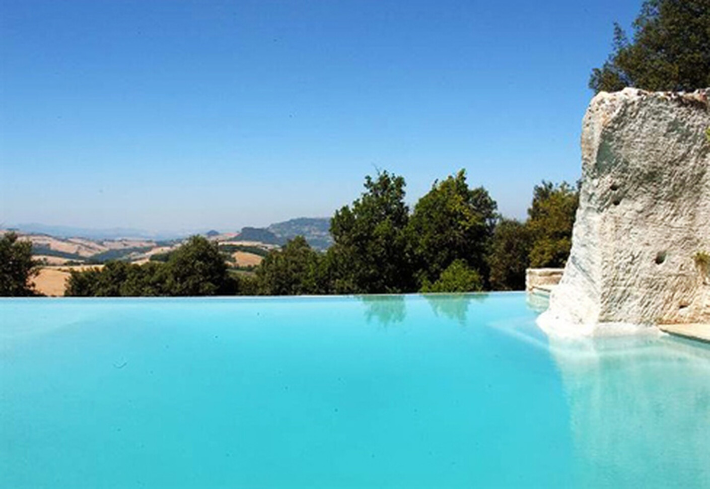 Overflow swimming pool with stone trim by Indalo Piscine | STYLEPARK